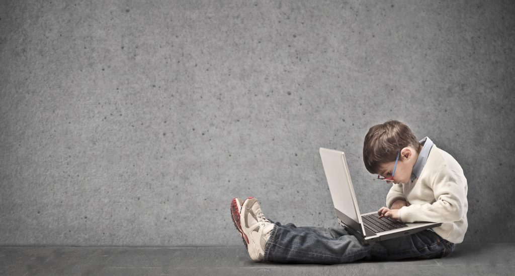 Child using a laptop computer with a dark white background - #DigCitUtah